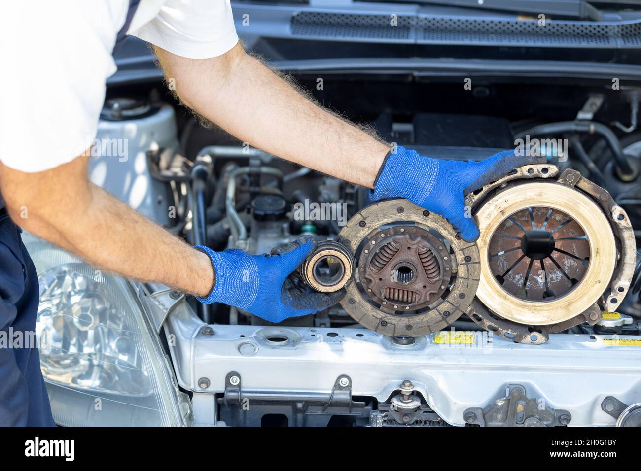 Auto mechanic holding used car pressure plate, clutch disc and release ...