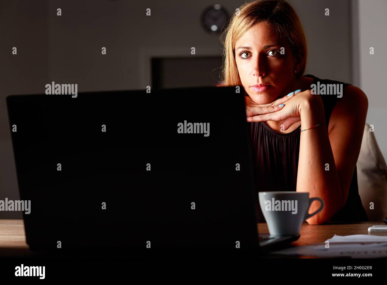 Dedicated businesswoman working late into the night seated at her ...