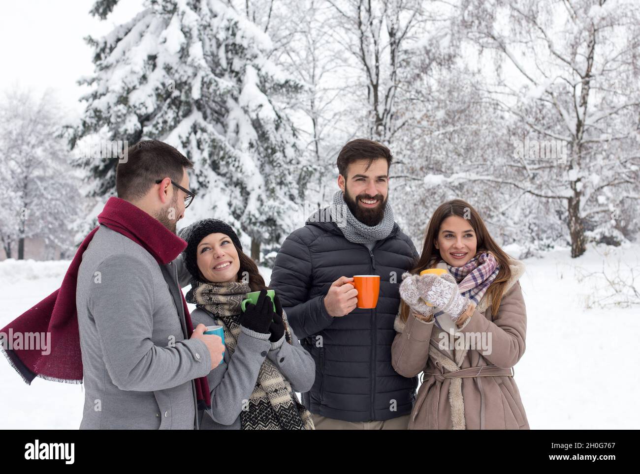 Small group of friends drinking hot chocolate on snow in forest Stock ...