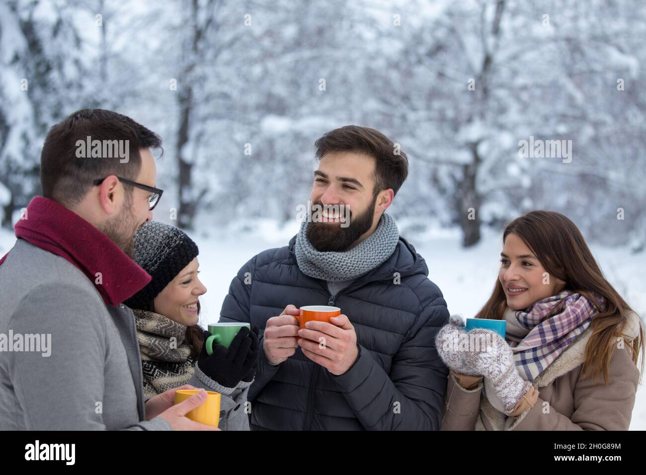Small group of friends drinking hot chocolate on snow in forest Stock ...