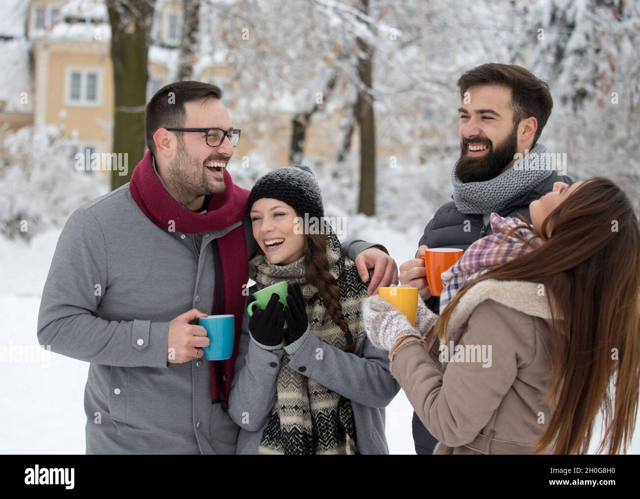 Small group of friends drinking hot chocolate on snow in forest and ...