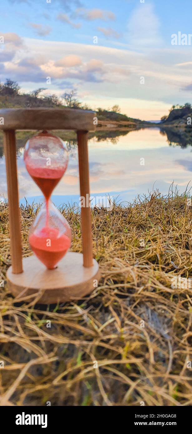 Vertical shot of an hourglass on thatches behind the river Stock Photo ...