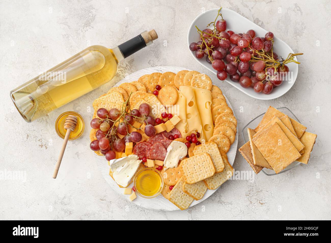 Platter with crunchy crackers and bottle of wine on light background ...