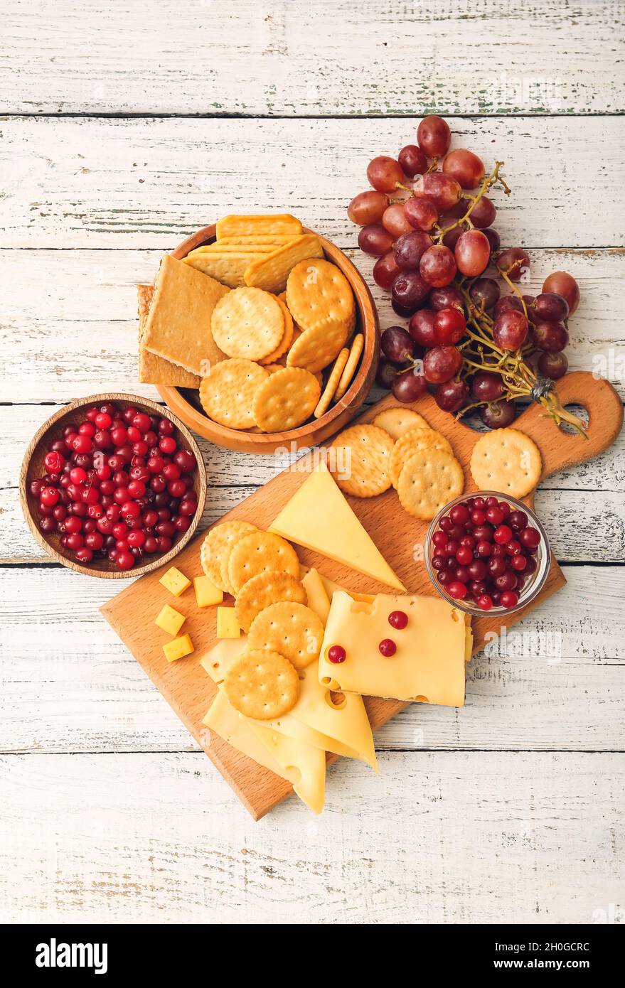 Crunchy crackers with cheese and cranberry on white wooden background ...