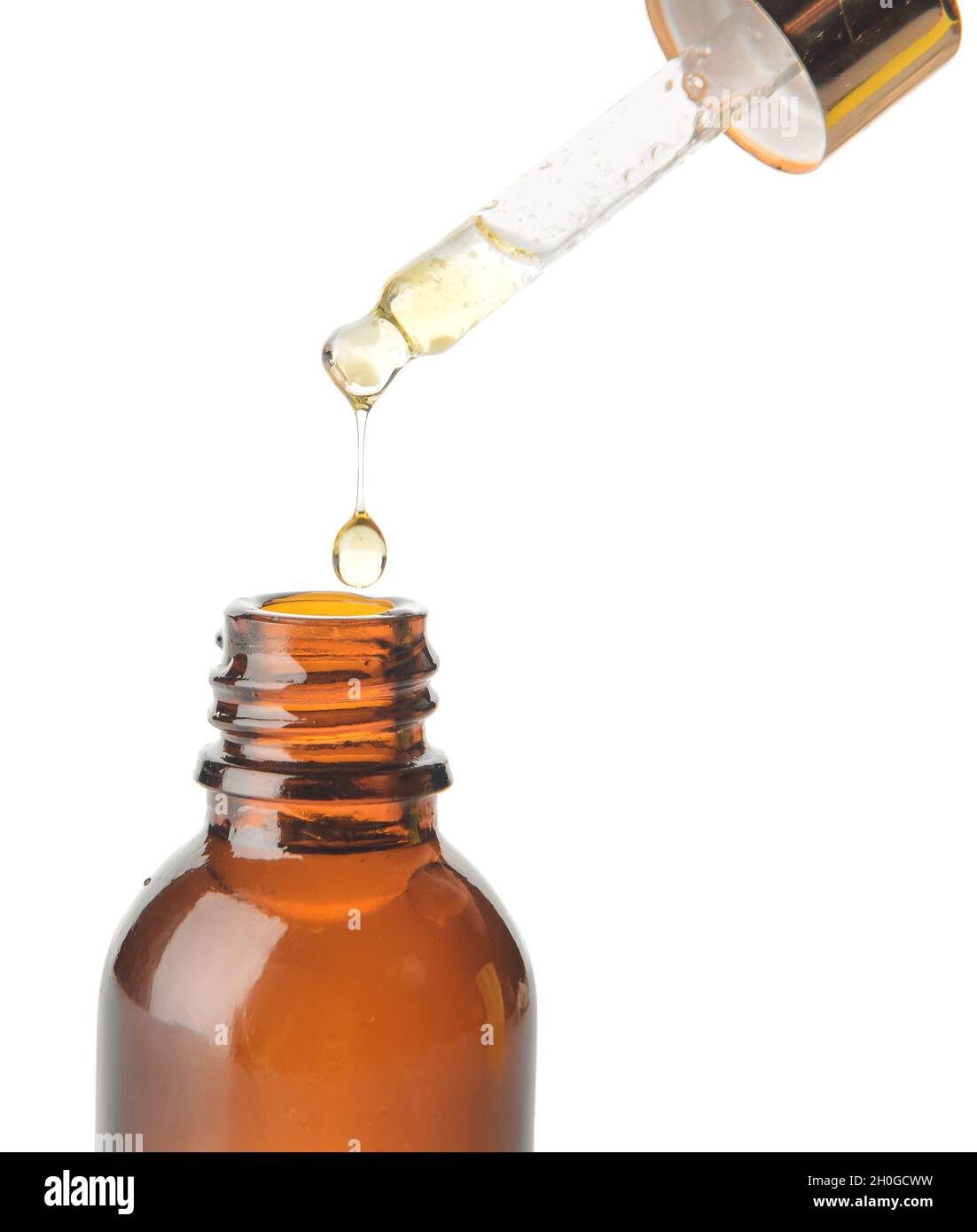Dripping of essential oil from pipette into bottle on white background ...