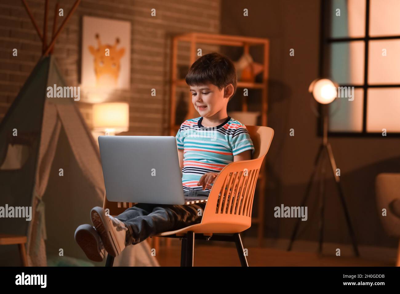 Little boy watching cartoons on laptop in chair at night Stock Photo ...