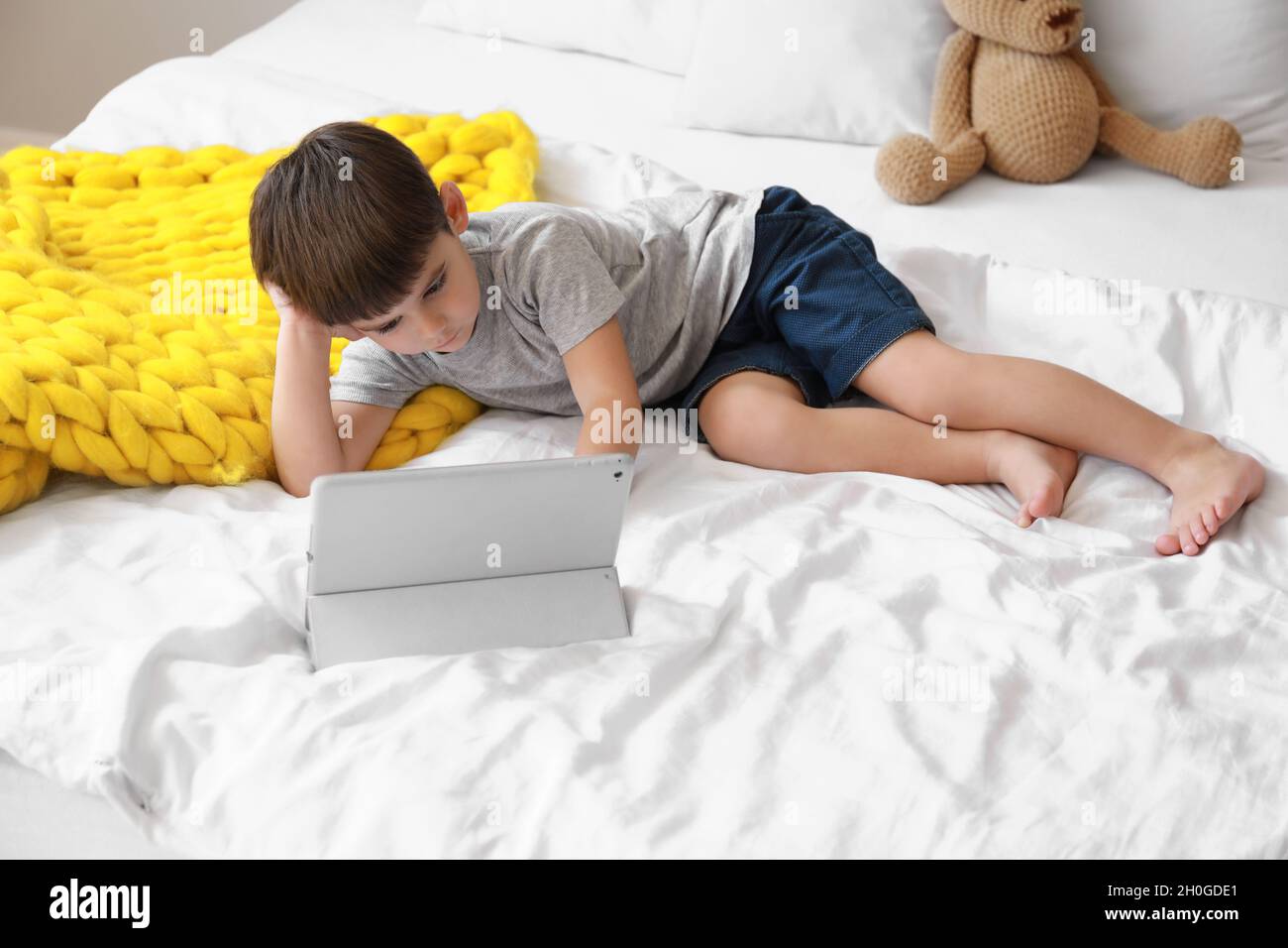Little boy watching cartoons on tablet computer in bedroom Stock Photo ...