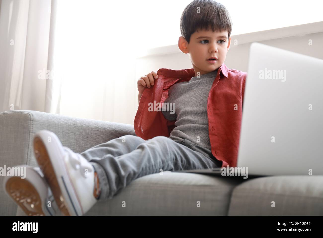 Little boy watching cartoons with laptop on sofa in living room Stock ...