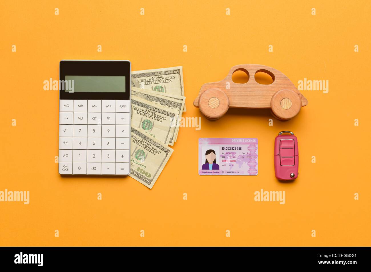 Wooden car, driving license, calculator and money on orange background ...