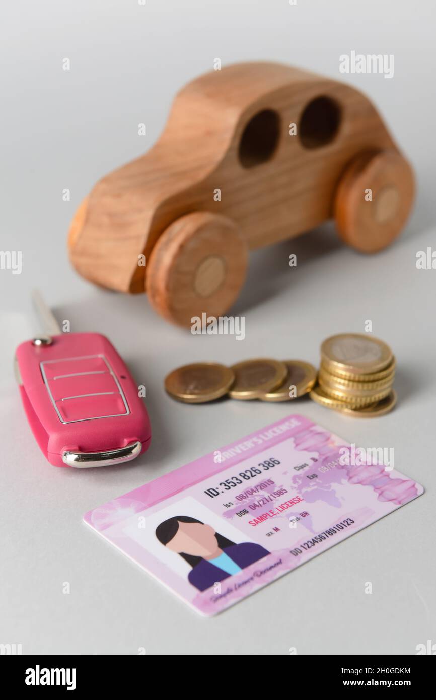 Driving license with key, coins and wooden car on light background ...