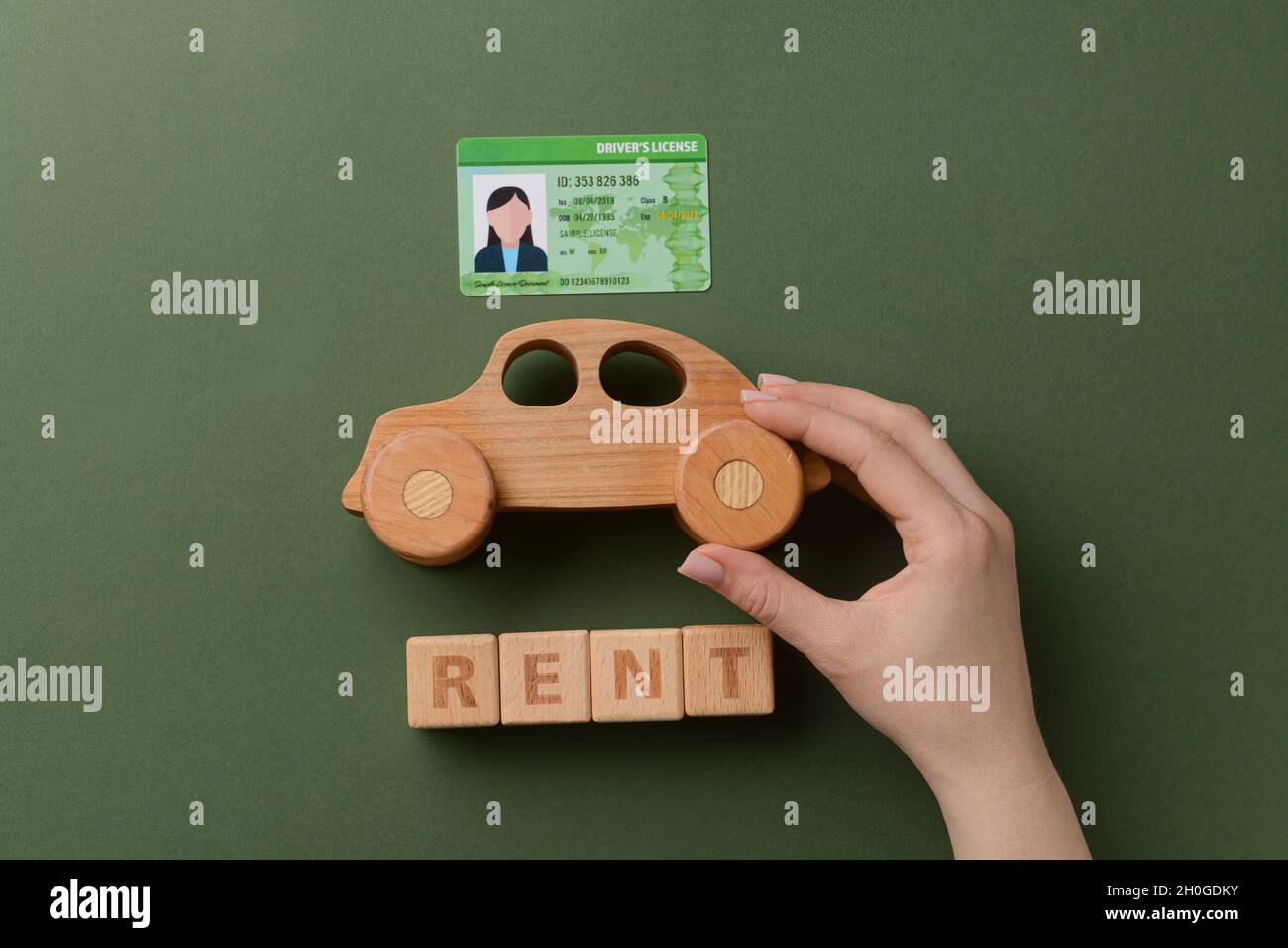 Woman with wooden car, word RENT and driving license on green ...