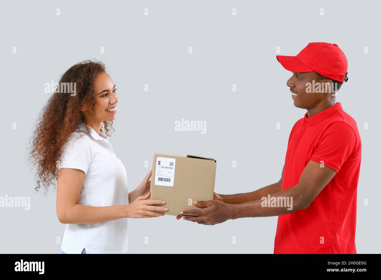 Customer receiving parcel from courier on grey background Stock Photo ...