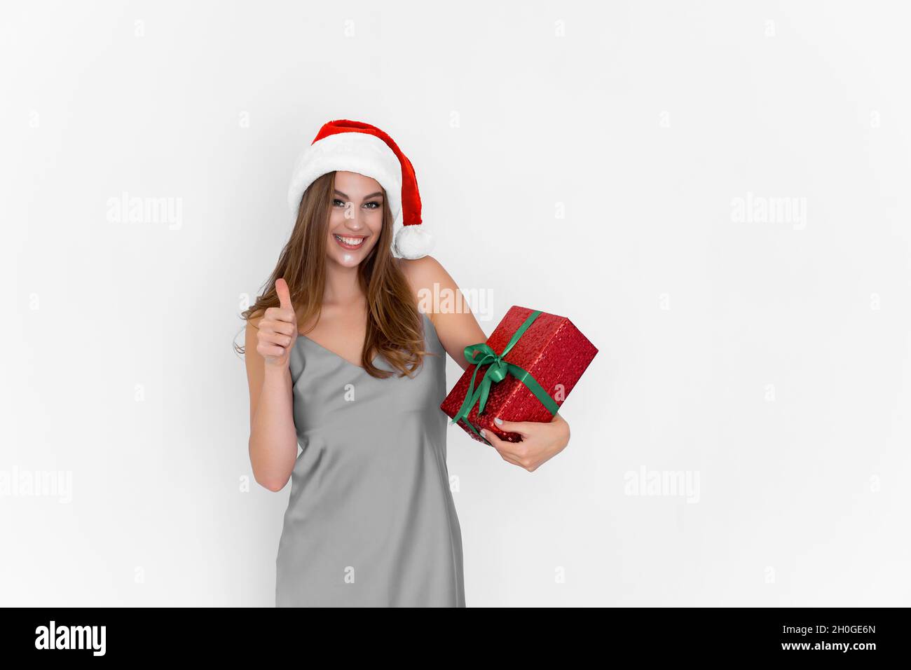 Happy smiling positive Santa girl holds gift box while gestures thumb ...