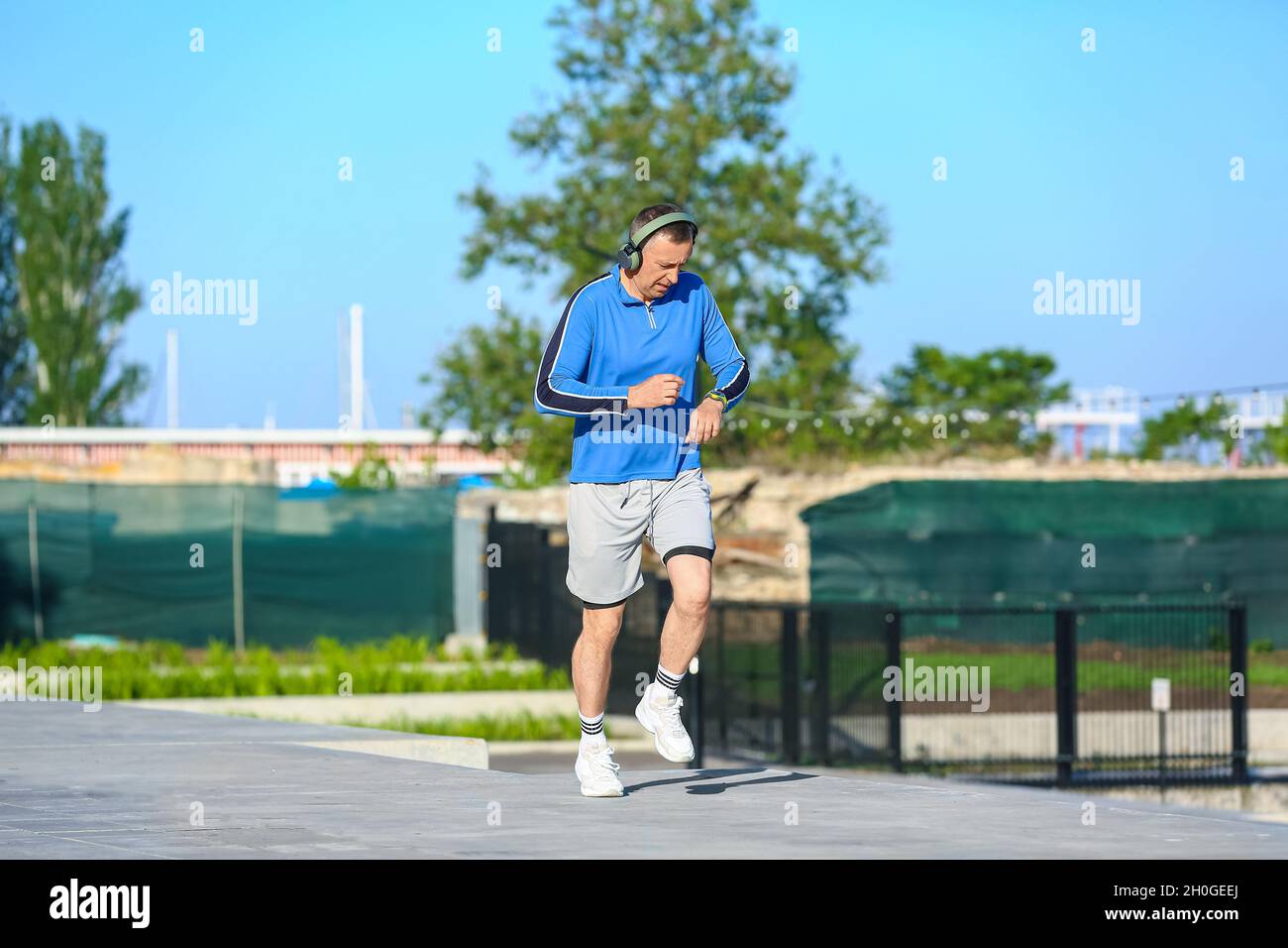 Sporty mature man in headphones running outdoors Stock Photo - Alamy