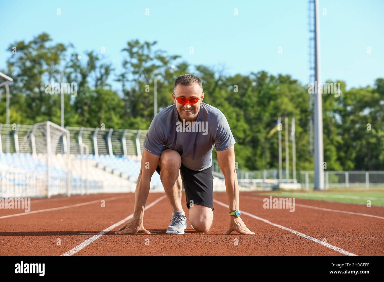 Sporty mature man getting ready to run at stadium Stock Photo - Alamy