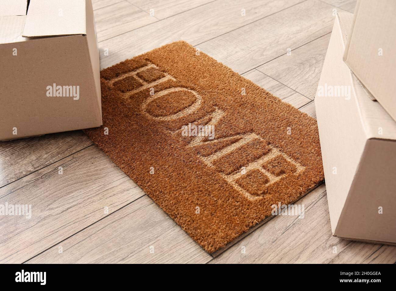 Parcel boxes and door mat on floor Stock Photo - Alamy