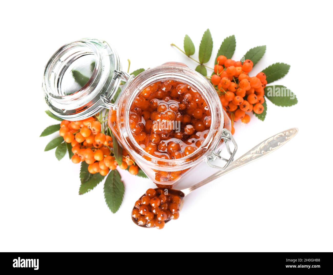 Glass jar and spoon with tasty rowan jam on white background Stock ...