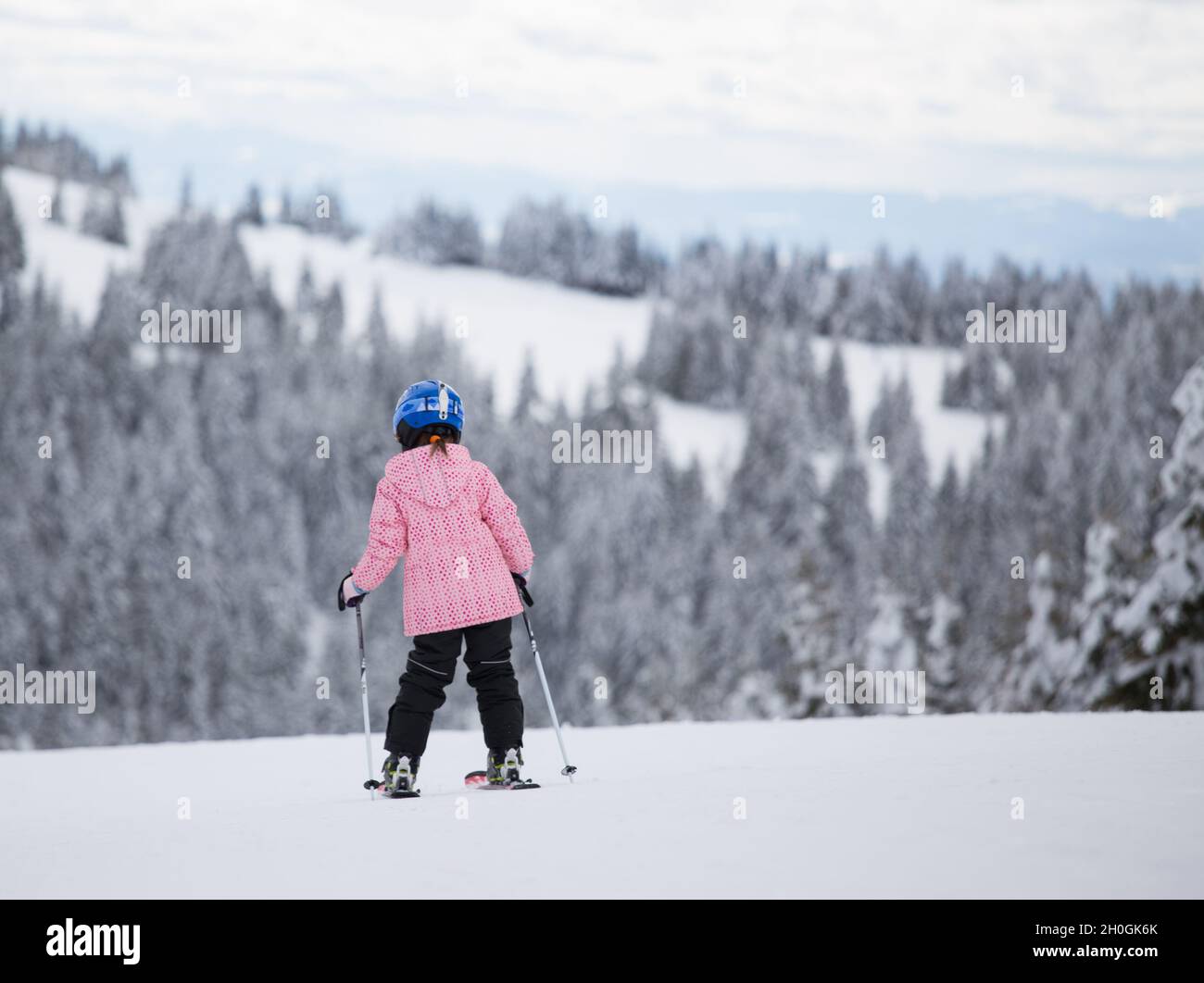 Rear view of girl skiing on slopes of Kopaonik mountain in Serbia ...