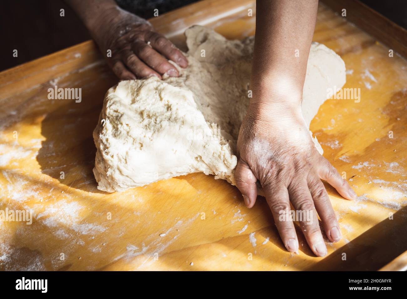Old woman's hands kneading bread dough. Empanadas. Wooden table Stock ...