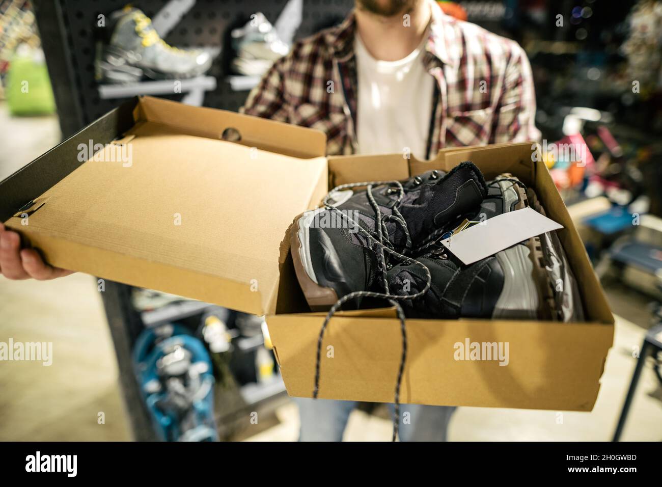 Store clerk helping customer try hiking boots at outdoors equipment ...