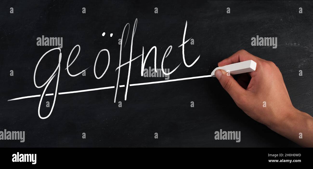 The word open is standing in german language on a chalkboard ...