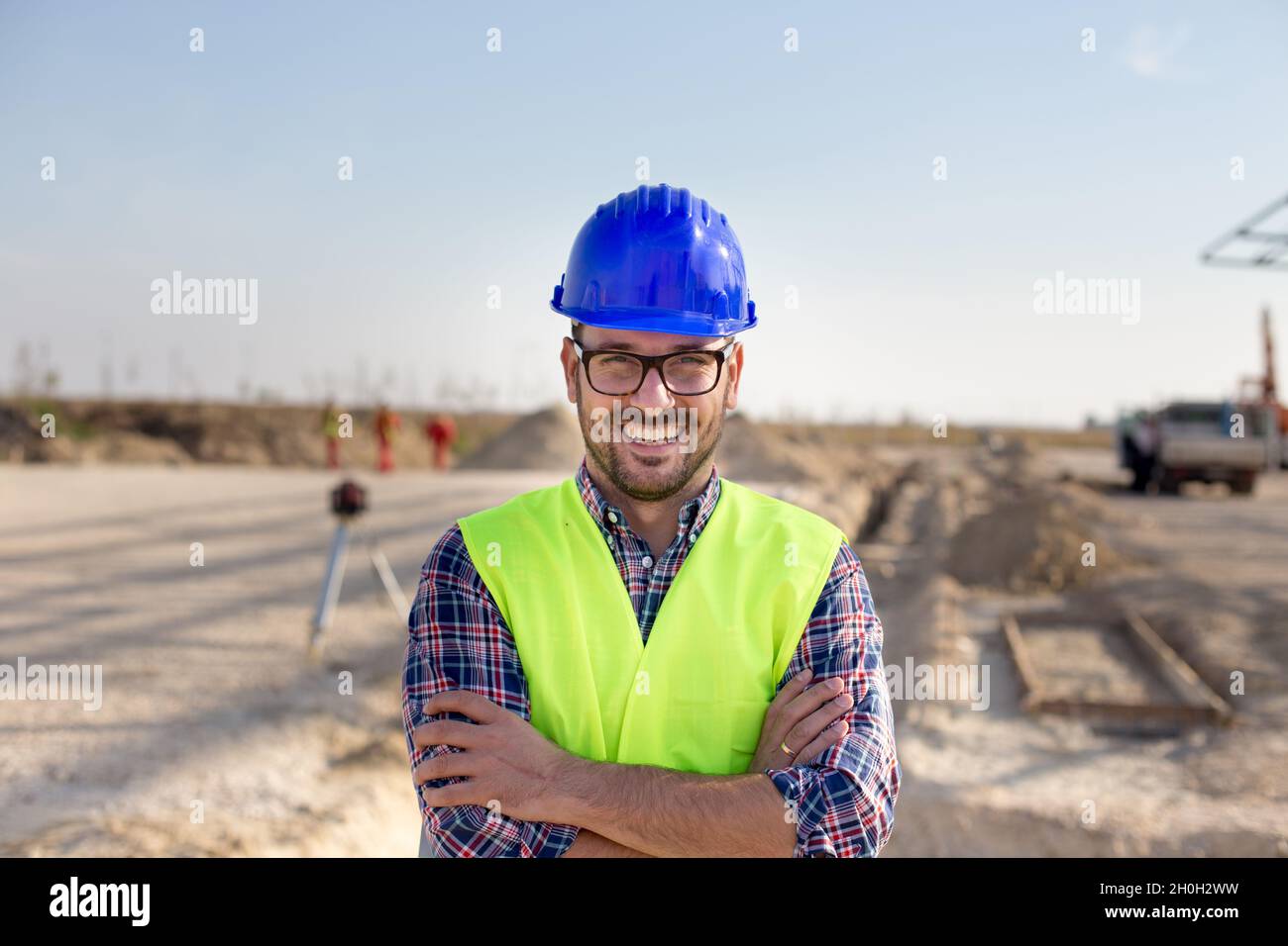 Portrait of satisfied and confident engineer with helmet and vest on ...