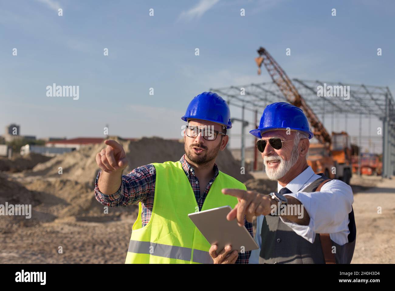 Two satisfied engineers talking at building site with construction ...