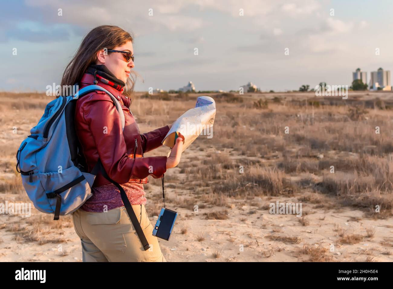 Scenic shot of a Caucasian woman traveler holding a map and wearing ...