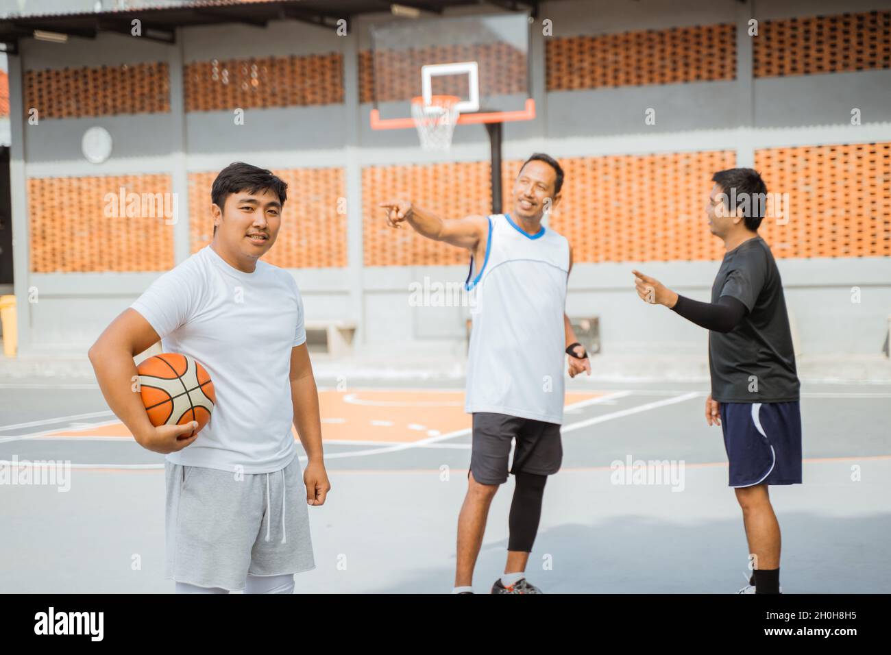 basketball player holding a ball while standing Stock Photo - Alamy