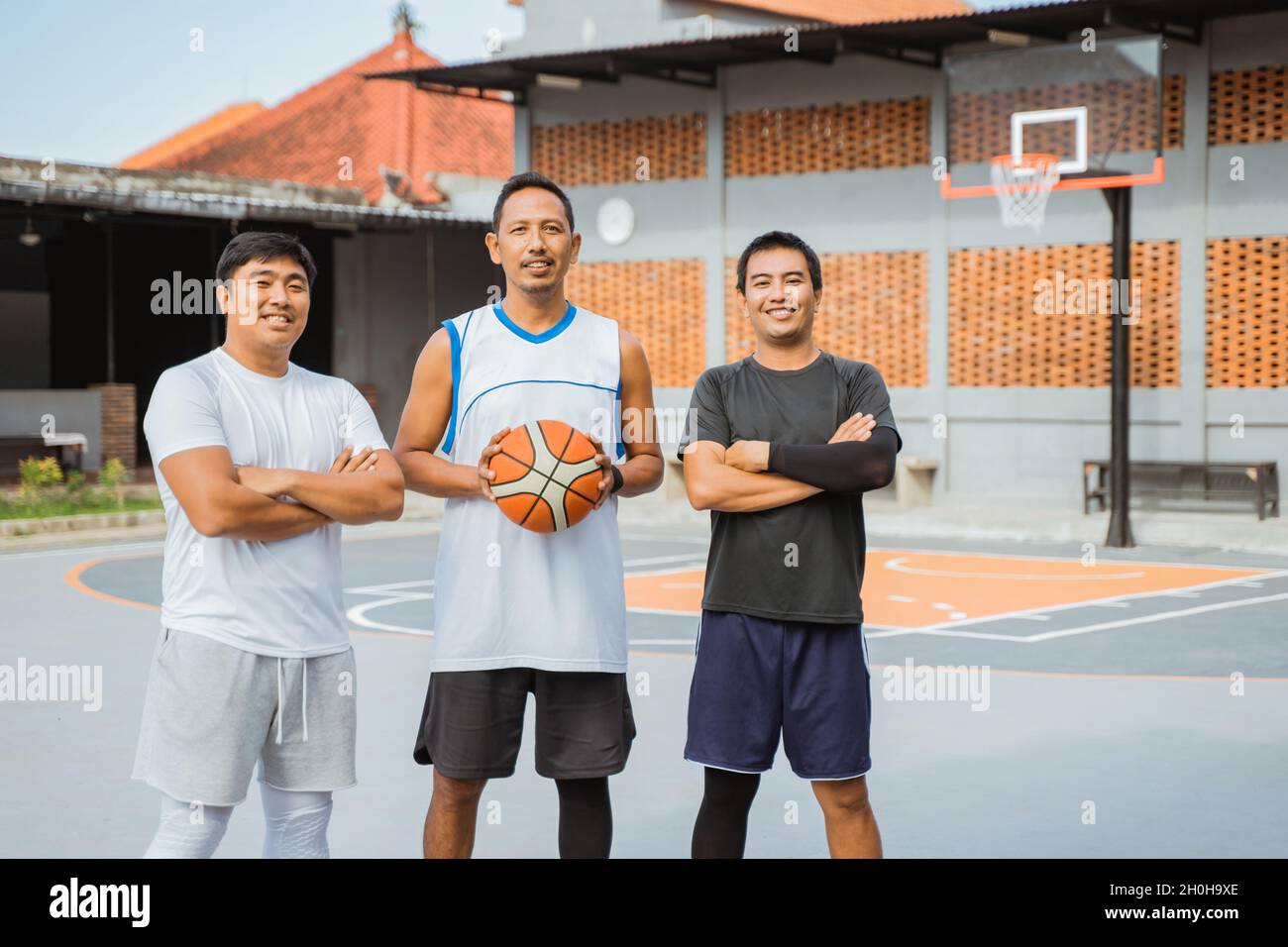 a coach and two smiling basketball players carrying a basketball Stock ...