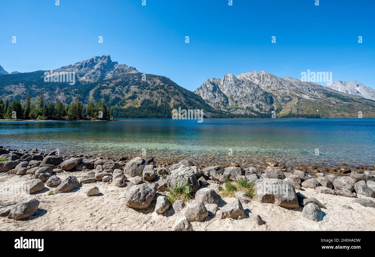 Mountain range behind lake, shore of Jenny Lake, Grand Teton mountain ...