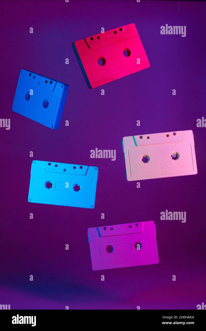 Colored audio cassettes hanging in the air against purple background ...