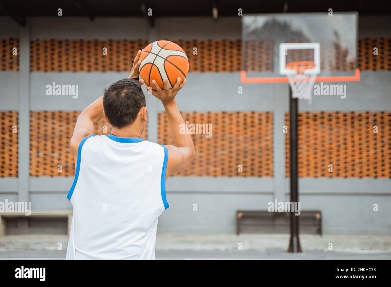back view of a basketball player holding the ball while jump shot into ...