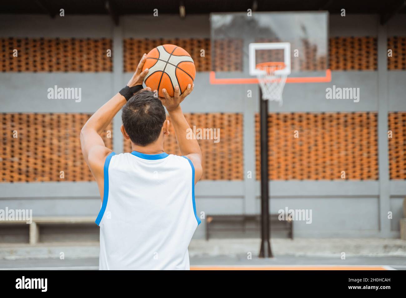 back view of a male basketball player holding the ball while shooting ...