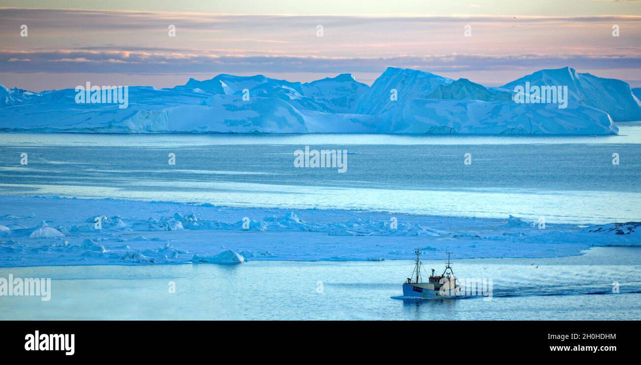 Fishing boat in front of ice floes and icebergs, blue hour, winter ...