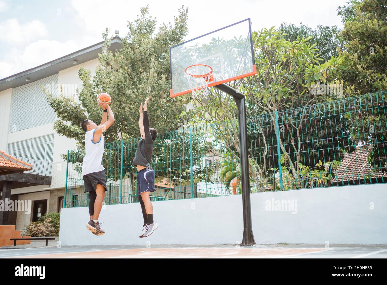 a male basketball player takes a jump shot and is blocked by his ...