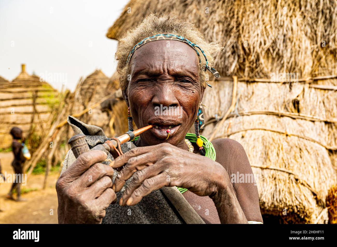 Old woman of the Jiye tribe smoking a pipe, Eastern Equatoria State ...
