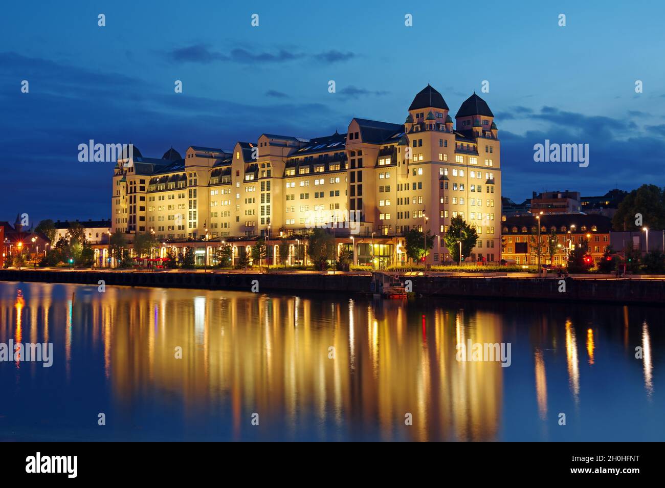 Large building at the harbour reflected in the water, dusk, former ...