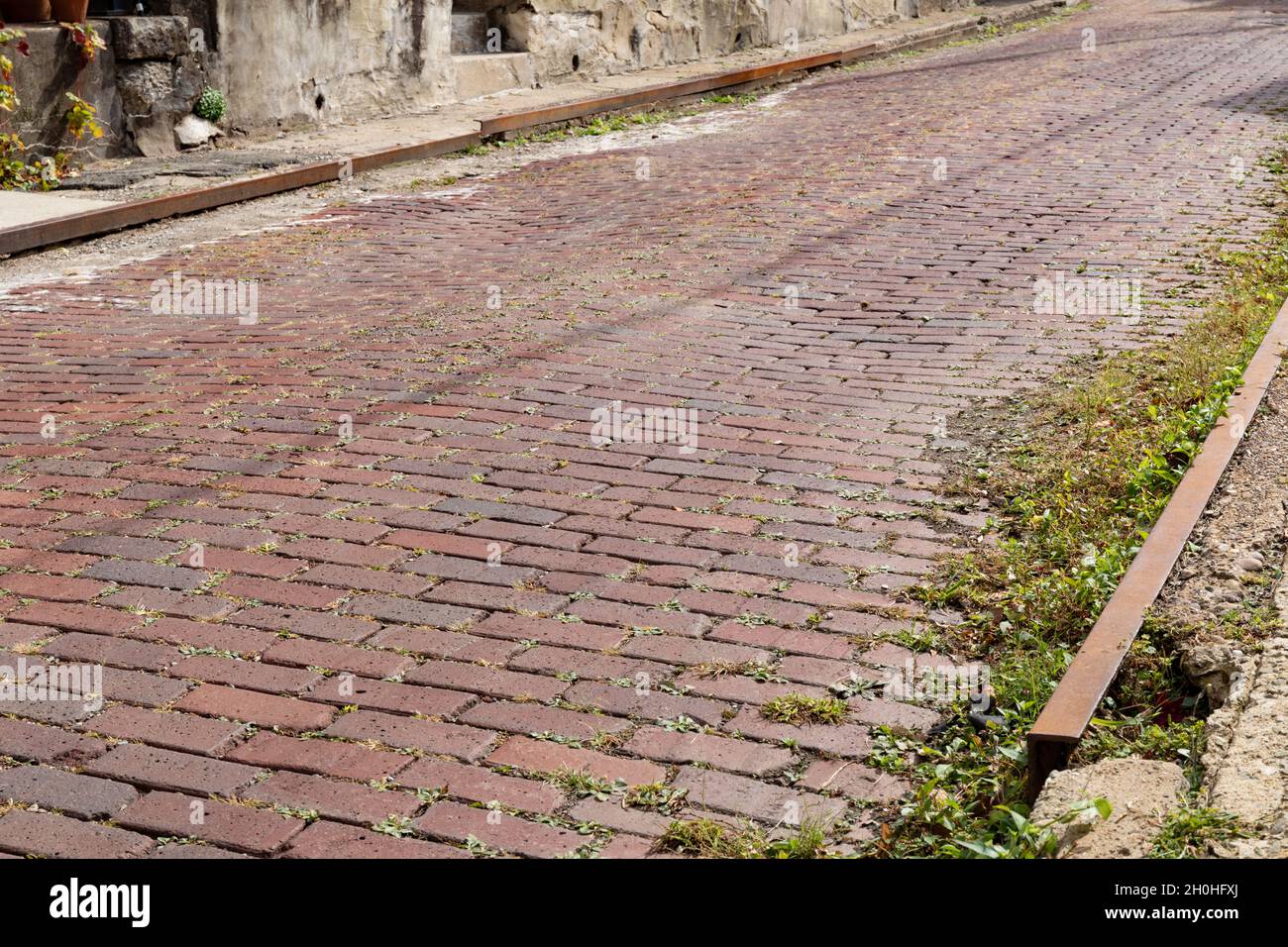 Old red brick street in running bond pattern, crumbling aggregate ...