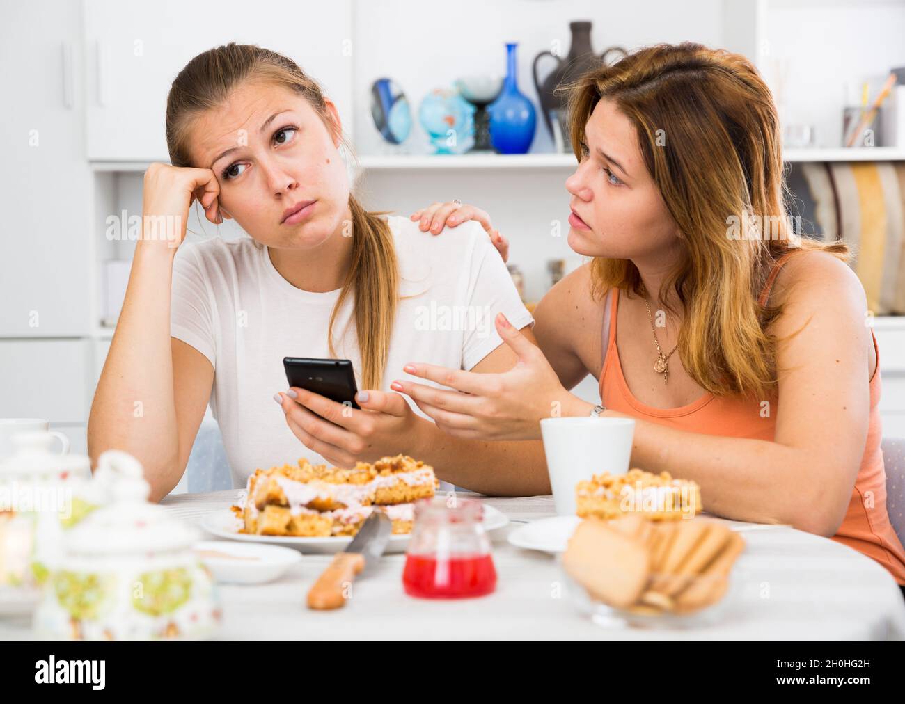female talking with sad friend with mobile Stock Photo - Alamy