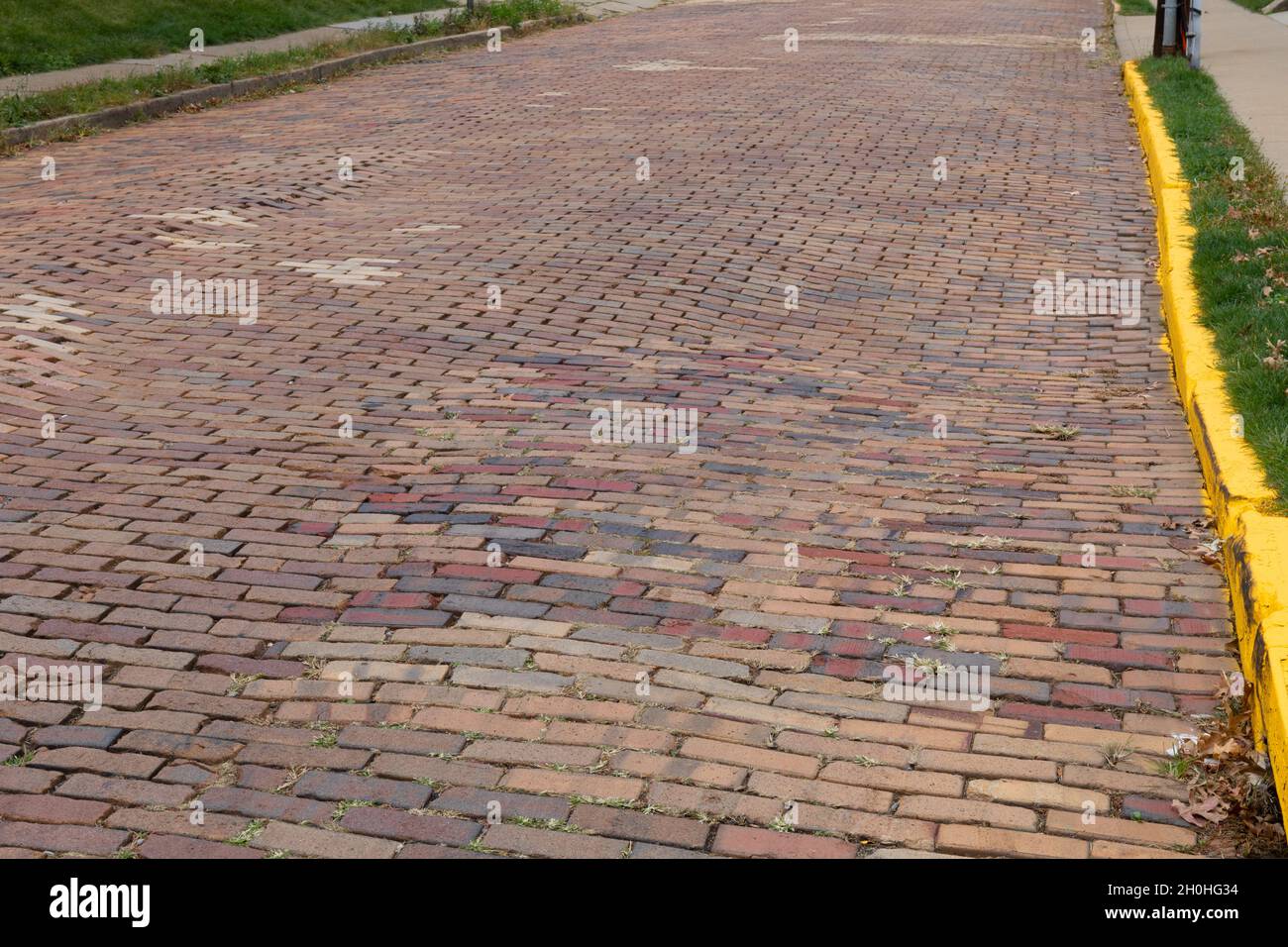 Undulating and settled road surface of old red brick, repairs in odd ...