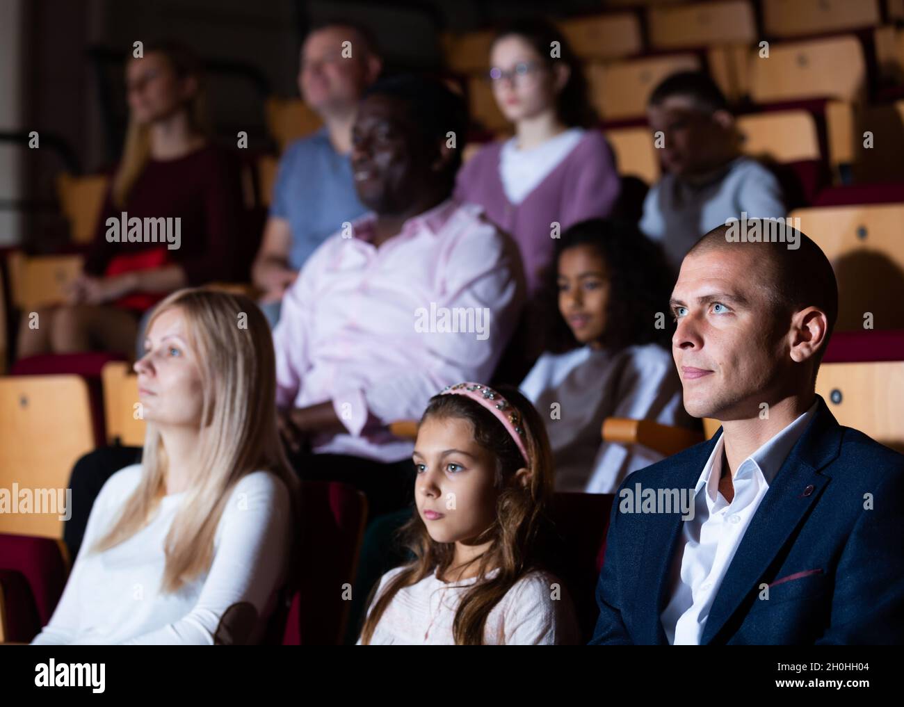 Father, mom and daughter are carefully watching spectacle or concert in ...