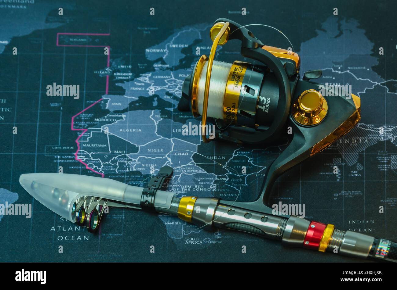 folded telescopic fishing rod with a reel lies on a world map on a ...