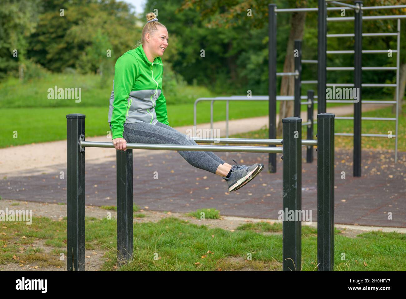 Athletic woman in her forties working out on parallel bars at an ...