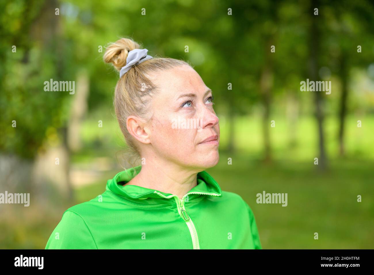 Thoughtful middle-aged blond woman with her hair tied in a top knot on ...