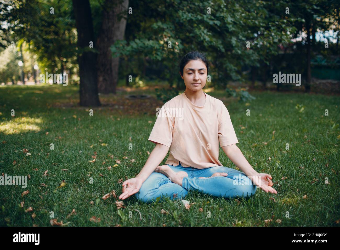 Indian woman doing yoga and meditation in lotus asana pose in outdoor ...