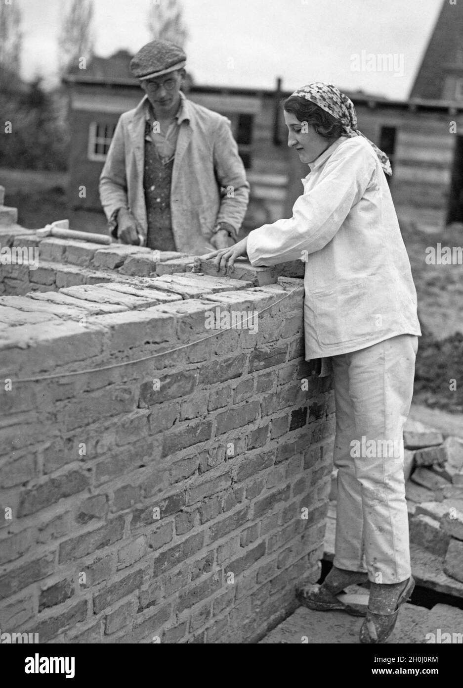A female apprentice bricklayer raising a wall in Berlin. [automated ...