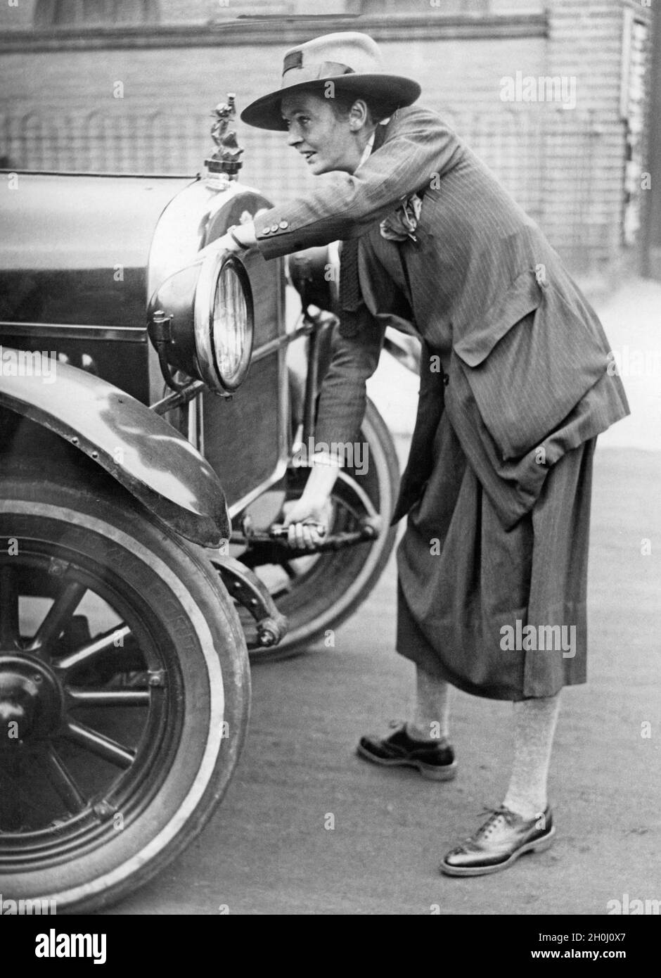 A driver starts the engine of her automobile with the crank. [automated ...