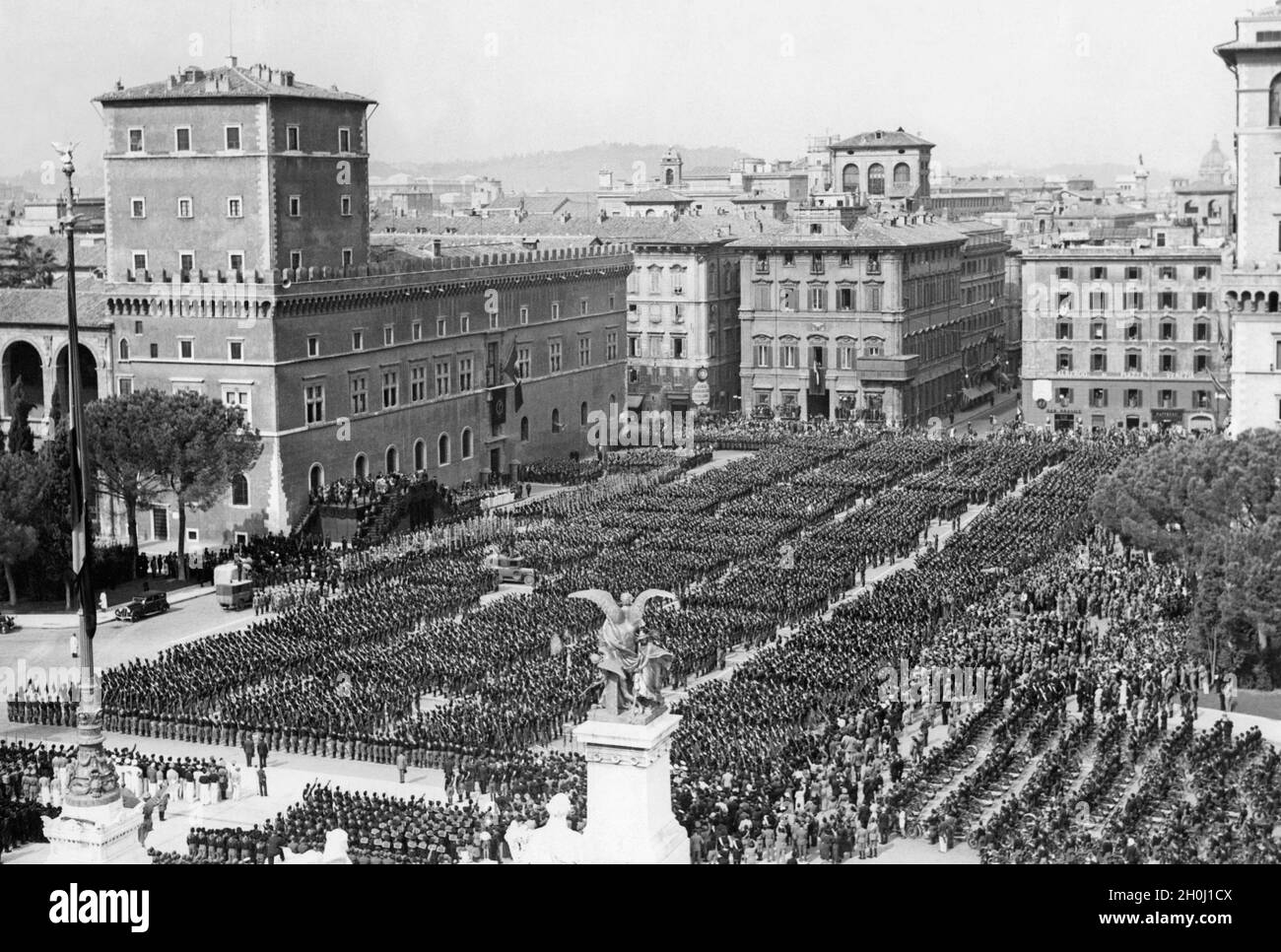 A parade has gathered in front of a speaker's stand standing in front ...