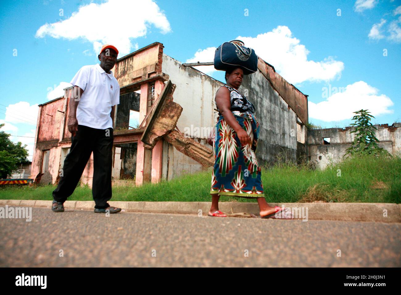 A couple walk pass a rundown former government building in Mocuba, Ile ...